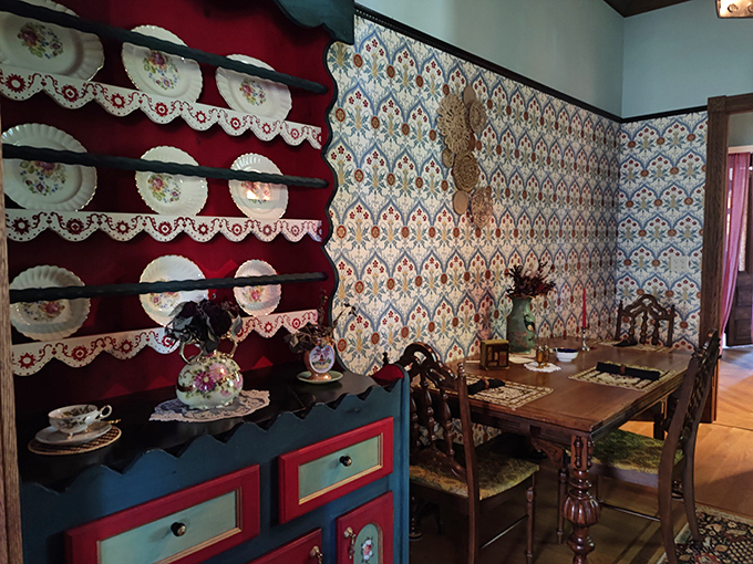Delicate china displayed against bold red shelving creates a striking visual in this dining area that blends Victorian charm with artistic flair.