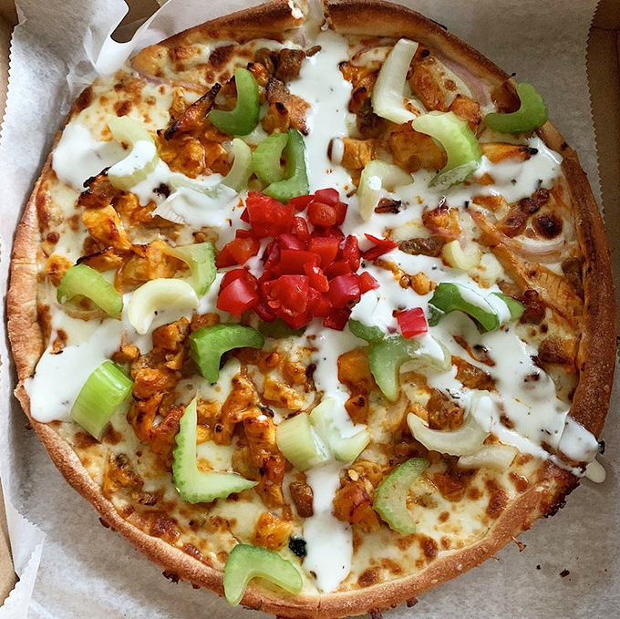 A white pizza featuring colorful bell peppers and chicken that's anything but bland. When your pizza looks like a work of art, eating becomes a cultural experience.