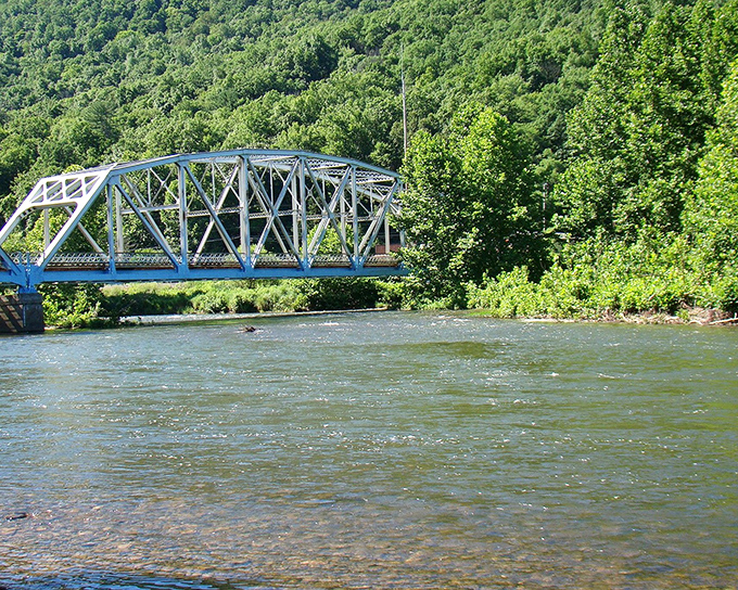 The blue bridge spans rushing waters, connecting not just two shores but visitors to experiences waiting on the other side.