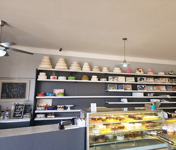 The cake display wall &ndash; where wedding dreams and birthday wishes take delicious form under careful fluorescent lighting.