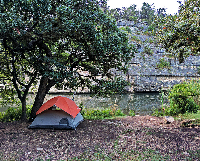 Camping beneath limestone cliffs where your tent becomes front-row seating to nature's greatest show: dawn over the Sabinal River.