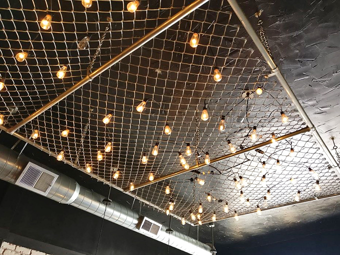 Not your average ceiling &ndash; fishing net and Edison bulbs create an unexpected maritime vibe. Proof that thoughtful design extends to every corner of this deli.