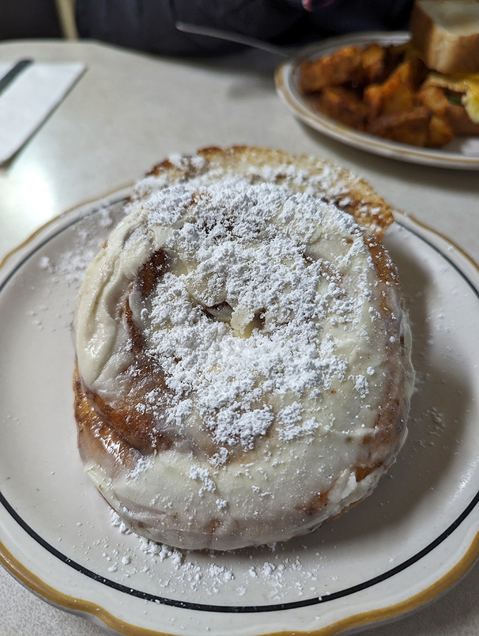 The cinnamon roll arrives dusted with powdered sugar like fresh Erie snowfall&mdash;a sweet spiral of dough that's been kissed by butter and transformed by heat. 