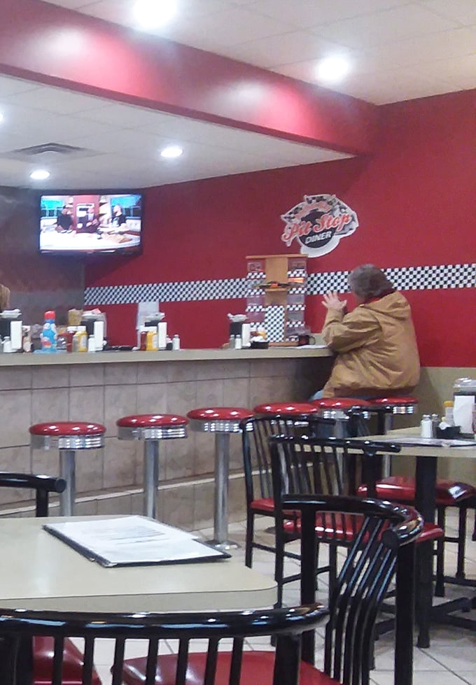 The counter seating – where solo diners become part of the Pit Stop family. Red stools and checkered accents create that classic American diner atmosphere we all crave.