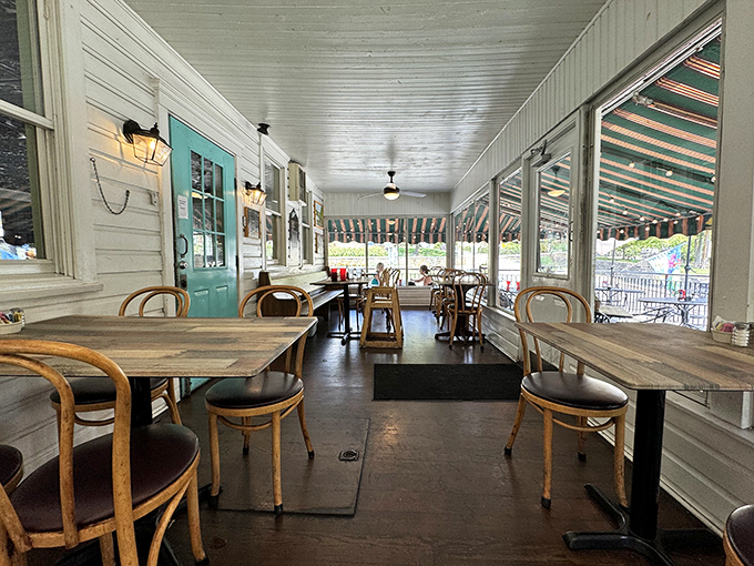 A screened porch that captures summer's essence &ndash; where wooden tables and vintage chairs invite you to linger over coffee long after your plate is clean.