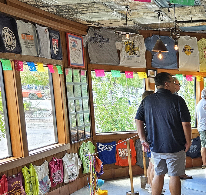 The T-shirt collection hanging like trophies – silent testimonials from sports teams who've experienced the burger bliss.