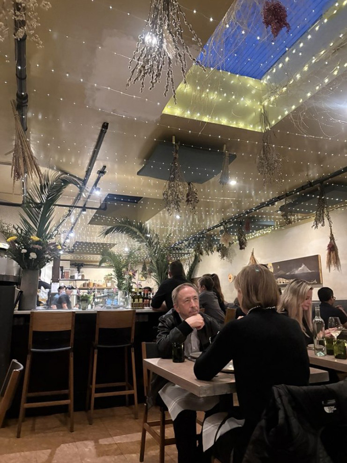 Under twinkling lights that mimic an Italian night sky, diners engage in the universal language of "mmm" and "you have to try this."