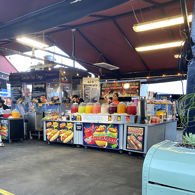 A carnival of flavors awaits at this vibrant food stand, where colorful aguas frescas promise sweet relief from swap meet adventures.