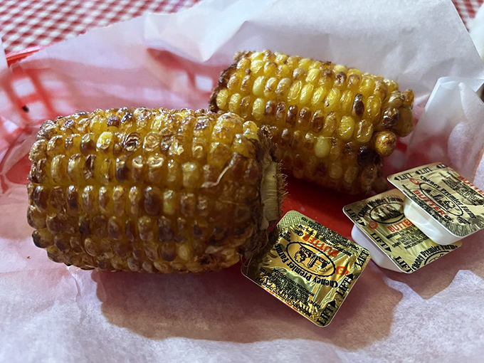 Grilled corn on the cob with butter packets standing by &ndash; nature's perfect hand-held side dish waiting for its moment in the spotlight.