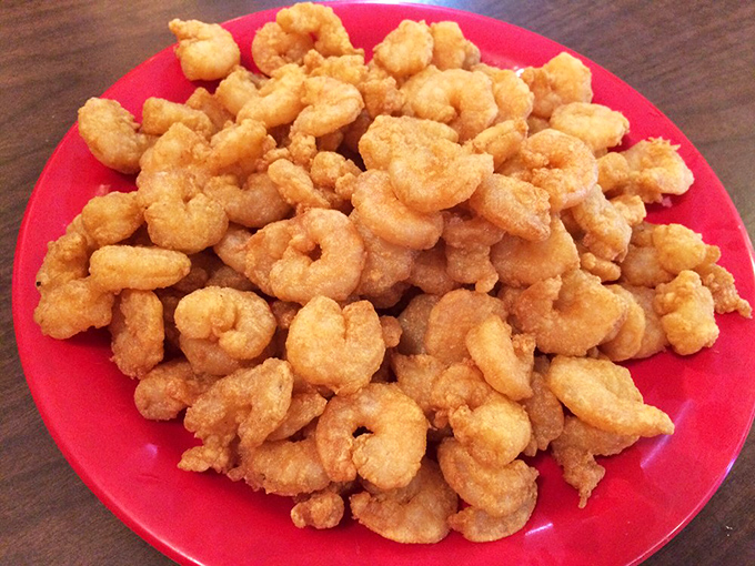 Fried shrimp piled high on a red plate &ndash; golden, crispy morsels that disappear faster than you can say "pass the cocktail sauce."