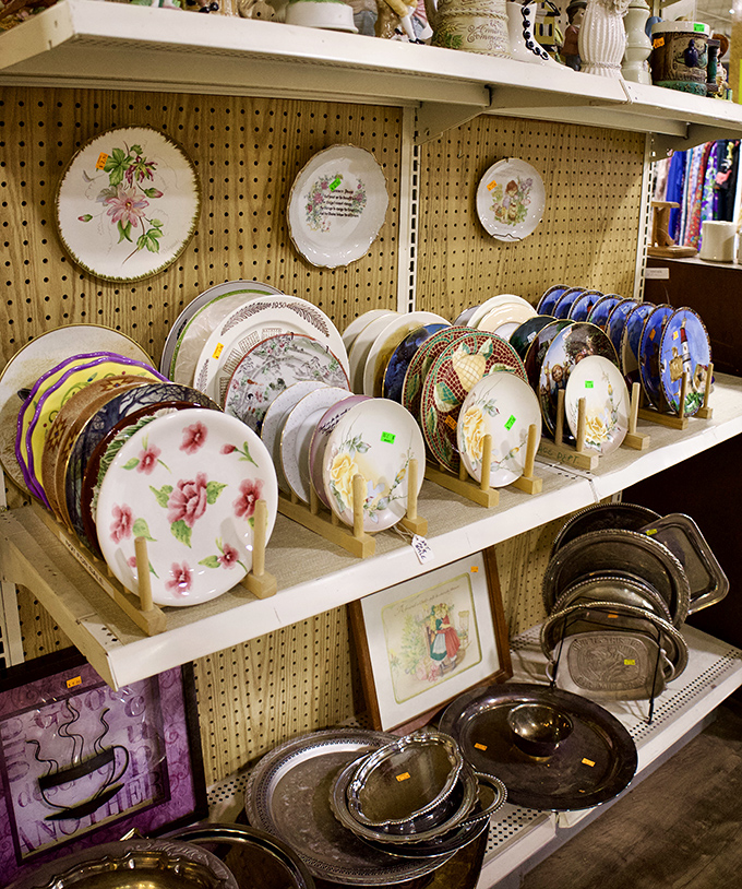 Decorative plates stand at attention, their floral patterns and vintage designs telling stories of dinner parties and Sunday meals from decades past.