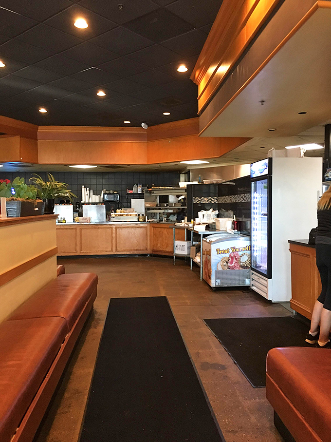 The open kitchen layout invites diners into the culinary conversation, with warm woods and orange tones creating that "stay awhile" vibe.