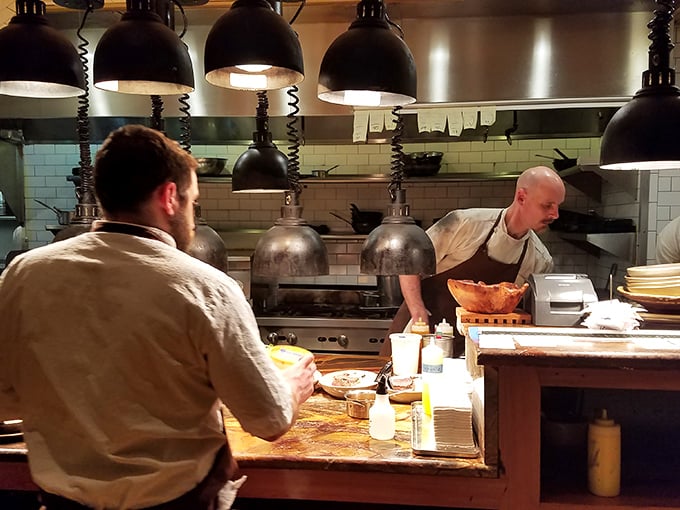 Kitchen choreography at its finest, where chefs transform Southern ingredients into edible poetry under the watchful glow of industrial pendant lights.