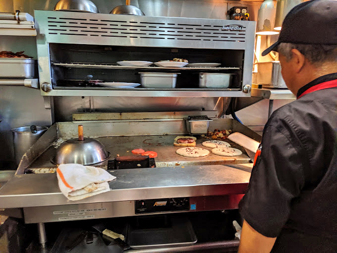 Behind the scenes, skilled hands work the griddle, creating comfort food magic one order at a time.