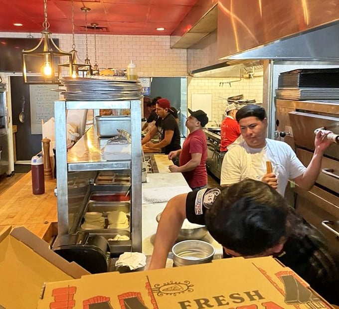 The open kitchen reveals the organized chaos where magic happens. Those pizza boxes aren't filling themselves, folks.