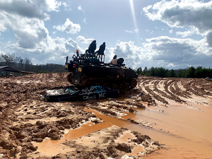 "Crush Me" reads the sign on a car about to meet its fate. In the mud-filled arena, mechanical beasts fulfill automotive revenge fantasies daily.