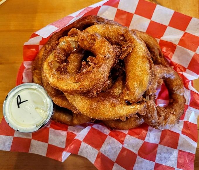 Onion rings stacked high like golden halos of crispy perfection that disappear faster than common sense.