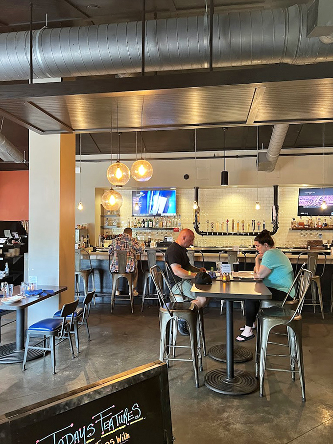 High-top tables and pendant lighting create intimate islands for conversation, while the exposed ductwork above reminds you this place is keeping it real.