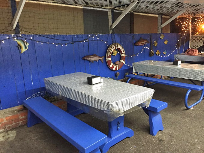 Blue picnic tables under string lights create an outdoor dining space that feels like a casual backyard fish fry&mdash;if your backyard had professional fryers.