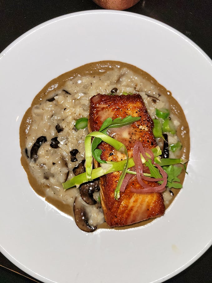 This salmon isn't just sitting on risotto – it's lounging on a creamy throne while vegetables pay their respects.