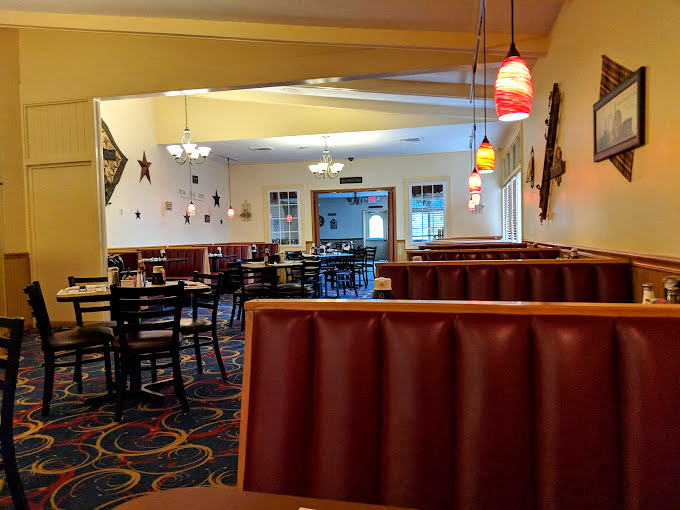 Cozy booths and tables spread across patterned carpet create distinct dining zones while maintaining that essential diner energy.