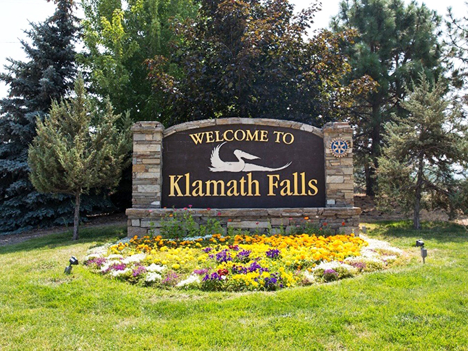 Klamath Falls welcomes visitors with flowers and a pelican sign, promising natural beauty that doesn't cost a fortune to enjoy.