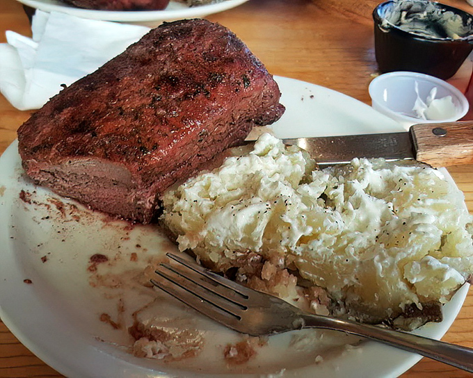 The humble baked potato, elevated to art form&mdash;fluffy interior, savory exterior, and the perfect companion to that magnificent steak.