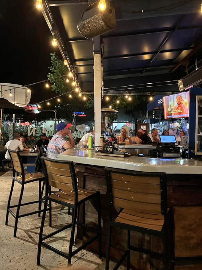 As night falls, the outdoor bar area transforms into a twinkling seafood oasis where cold drinks and ocean tales flow freely.