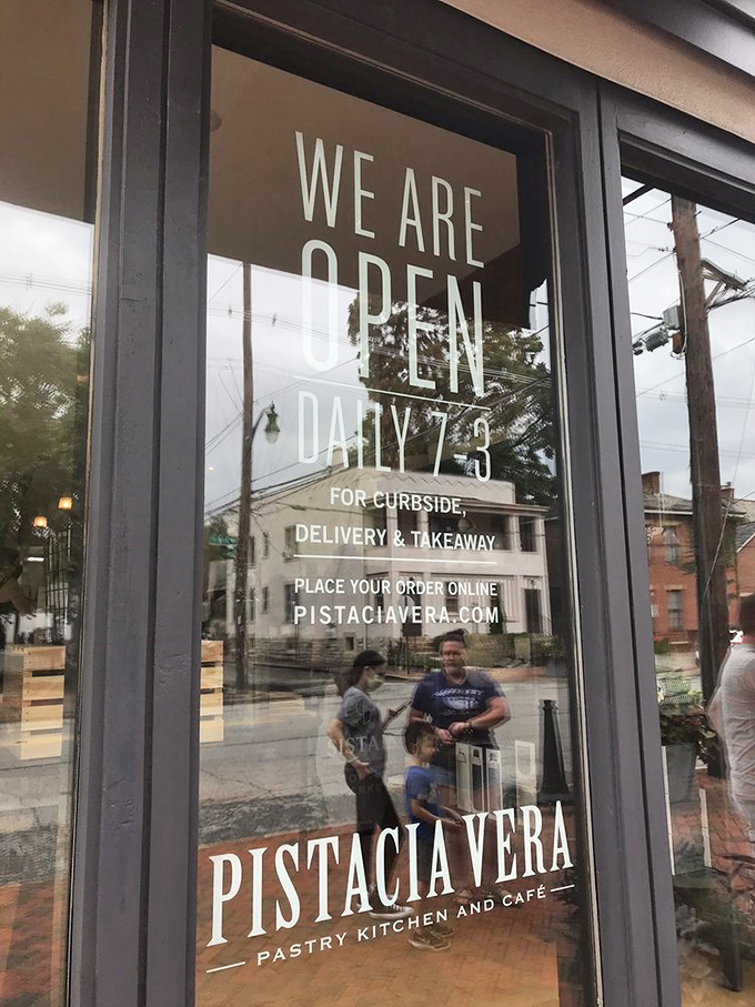 The door announces operating hours like a promise&mdash;"We Are Open Daily"&mdash;four words that bring comfort in an uncertain world.