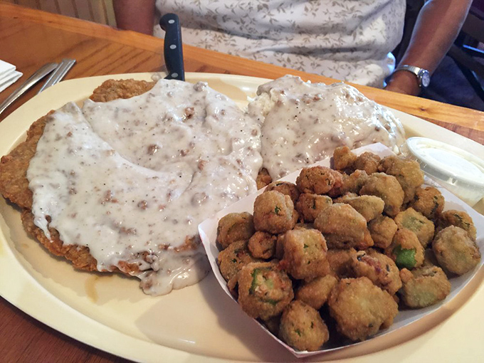 Country fried steak smothered in gravy alongside fried okra &ndash; a plate that says "I'm not counting calories today" in the most delicious way possible.