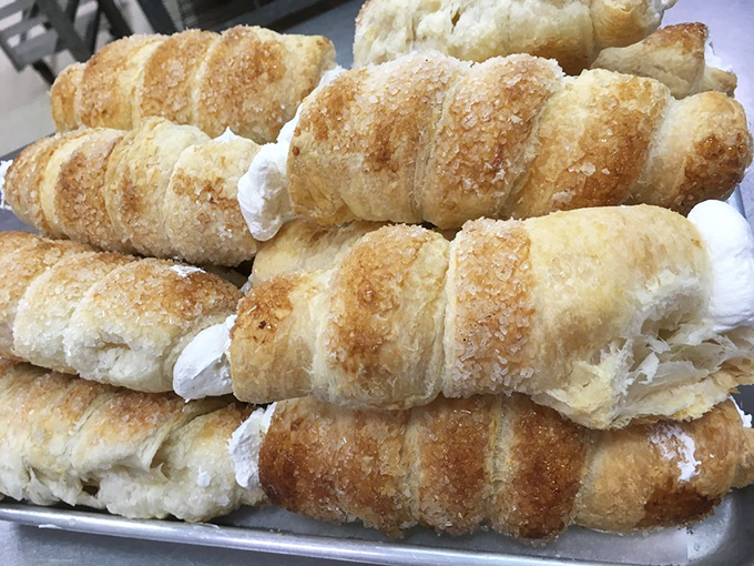Cream horns stacked like delicate instruments in a bakery orchestra. Each flaky layer conducts a symphony of sweetness.