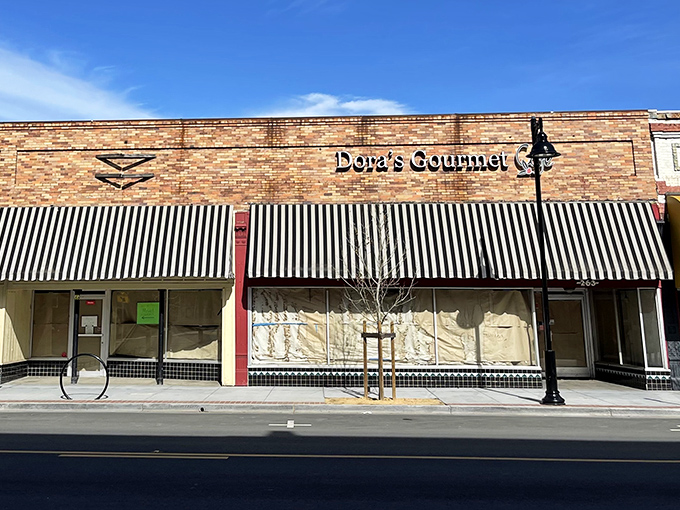 Dora's Gourmet sits quietly behind its striped awning, the culinary equivalent of that soft-spoken person at dinner who suddenly says something brilliant.