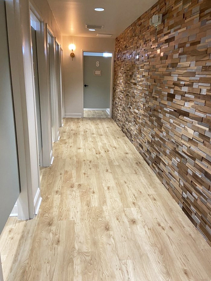 The hallway to transformation. These fitting rooms, flanked by warm wood and clean lines, are where secondhand possibilities become first-rate realities.