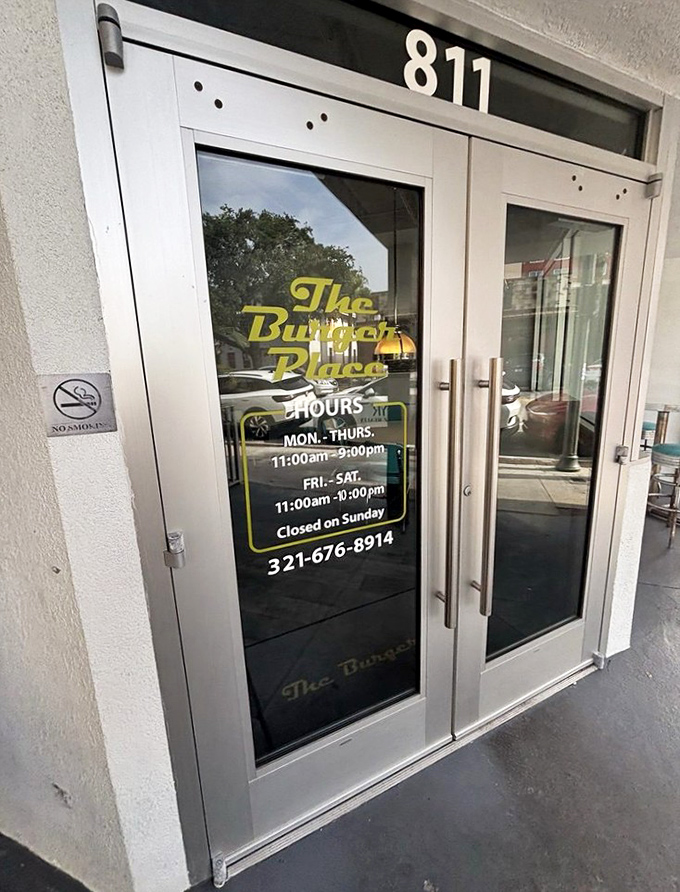 The entrance tells you everything you need to know: hours of operation, phone number, and the promise of burger happiness within.