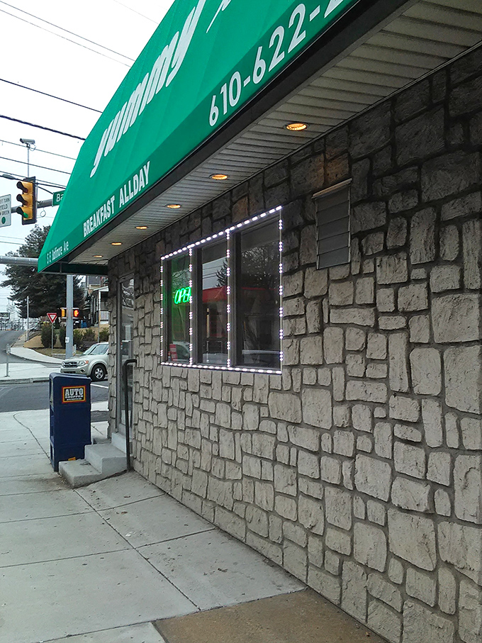 The distinctive green awning serves as a beacon for hungry travelers, promising breakfast salvation just steps from Baltimore Avenue.