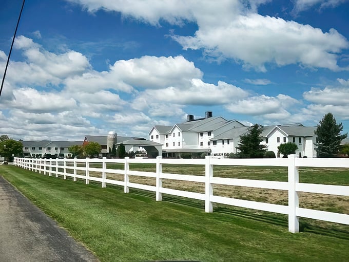 White fences and pristine buildings against Indiana sky. The Farmstead Inn embodies the clean lines and uncluttered aesthetic that defines Amish-inspired architecture.