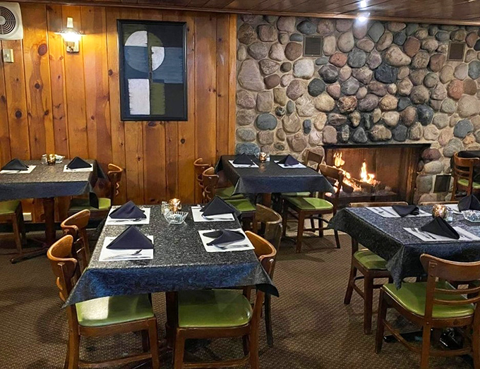 The stone fireplace dining area feels like eating in a luxurious cabin. Those green cushions add a pop of color that says "comfortable yet sophisticated."