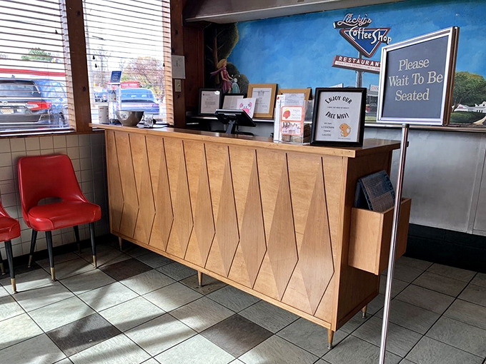 The modern reception desk maintains the vintage vibe. "Please Wait To Be Seated" – four words that promise good things ahead.