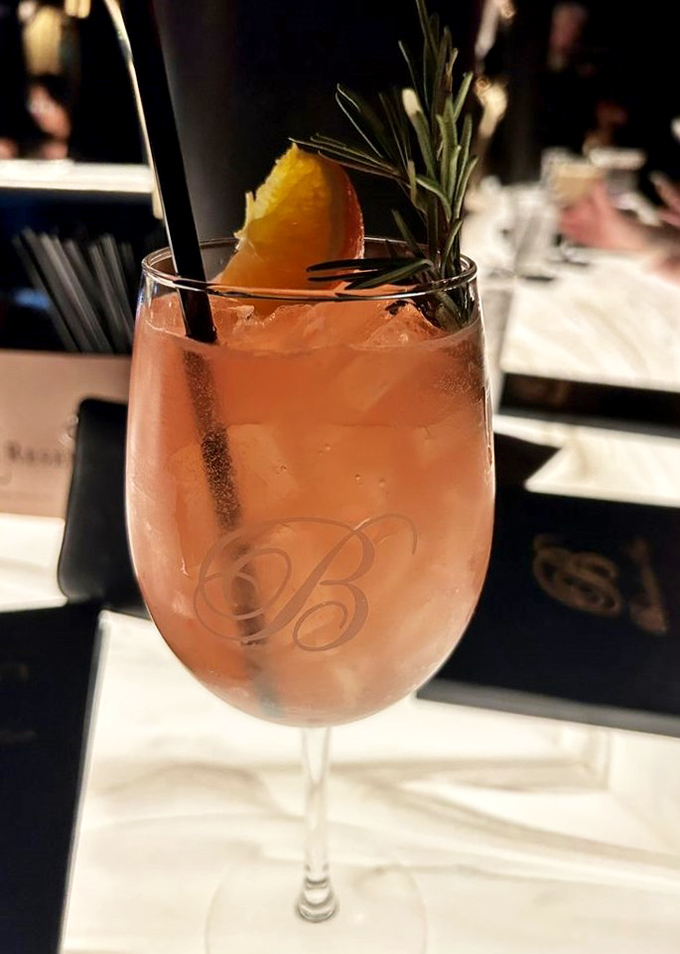 A cocktail garnished with rosemary and citrus&mdash;like a sunset in a glass that's dressed for a night at the symphony.