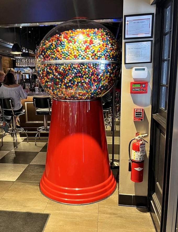 The giant gumball machine stands guard like a colorful sentinel, reminding you that adulthood still comes with candy privileges.