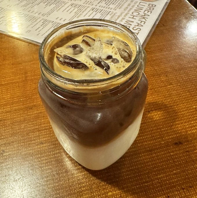 Iced coffee served in a mason jar&mdash;because sometimes morning salvation requires proper presentation and a healthy dose of caffeine.