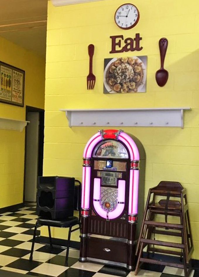 The jukebox stands guard beneath oversized utensils and a simple command that sums up the entire diner philosophy: "Eat."