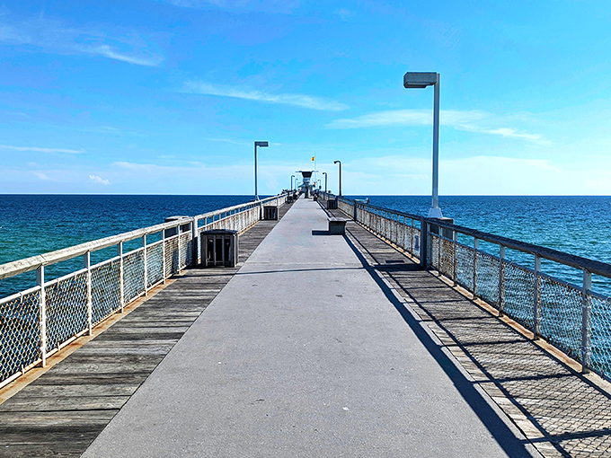 The fishing pier stretches toward the horizon like a runway for dreams, inviting you to walk just a little farther into the blue.