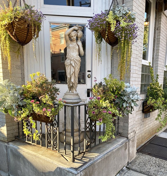 The classical statue stands guard like a sentinel of good taste, surrounded by flowers that could make a Roman emperor feel at home.