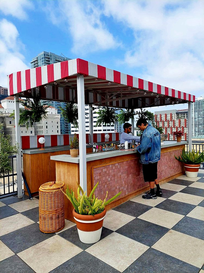 An outdoor bar with red and white stripes that says, "Yes, we're serious about cocktails, even when we're under the San Diego sun."