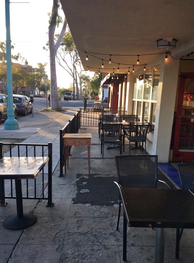 As evening falls, the patio transforms into an urban oasis where string lights twinkle above tables of happy diners enjoying San Diego's perfect weather.