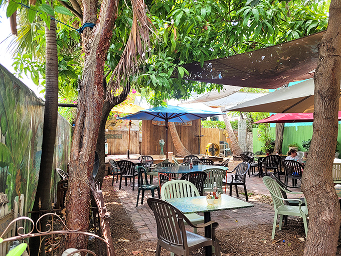 Dappled sunlight filters through tropical foliage, creating nature's air conditioning in an outdoor dining space that feels miles away from ordinary life.