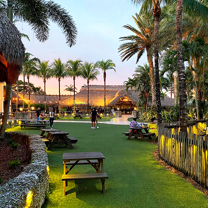Twilight transforms the grounds into a glowing tropical oasis. Those picnic tables have heard more good stories than most therapists.