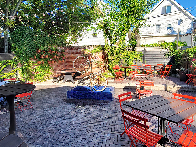 The patio feels like stumbling upon a secret garden where red chairs pop against brick walls and conversations flow as freely as the wine.