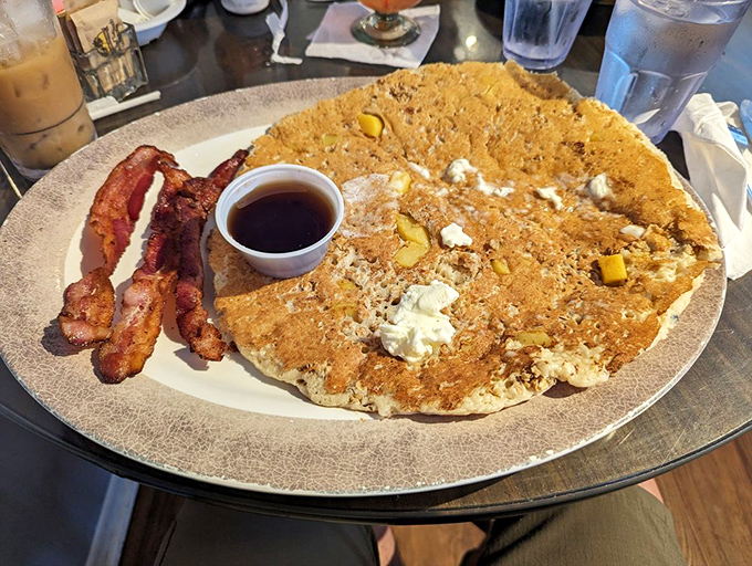 A pancake so massive it needs its own zip code, with bacon standing guard to prevent any maple syrup escapes.
